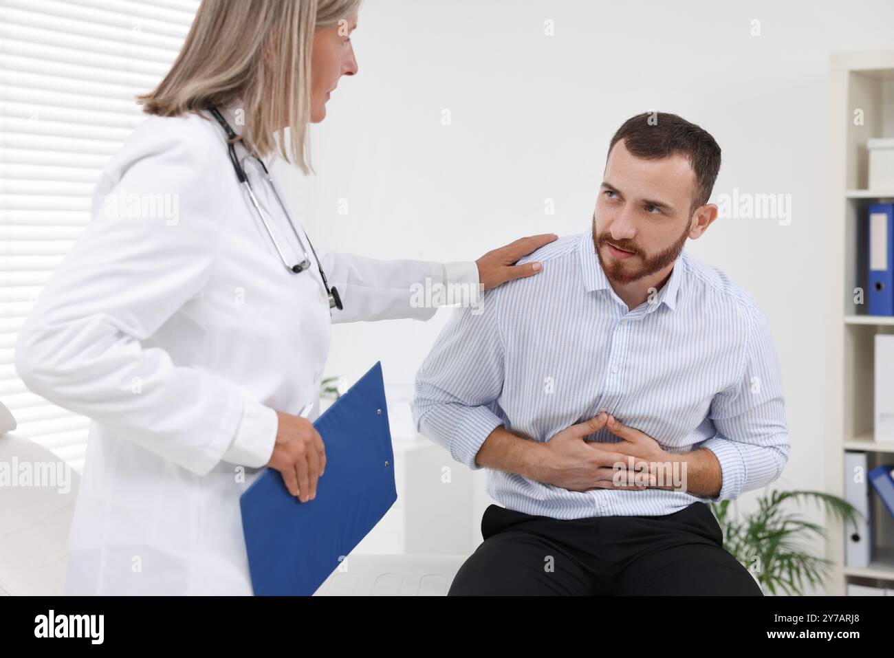 Doctor consulting patient with stomach pain in clinic Stock Photo - Alamy