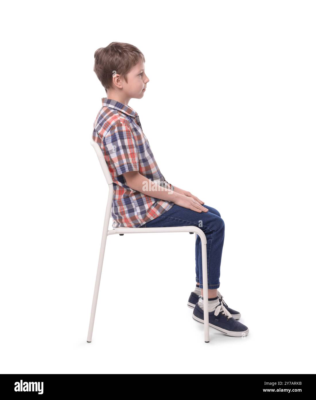 Boy with correct posture sitting on chair against white background ...