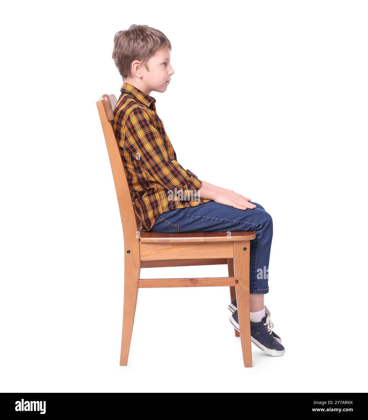Boy with correct posture sitting on chair against white background ...