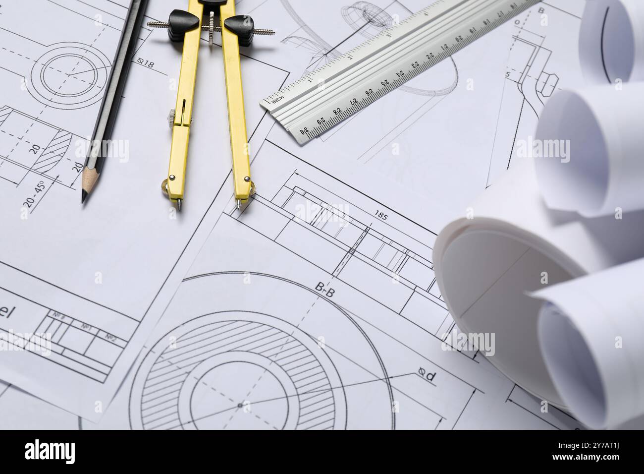 Different engineering drawings, ruler, divider and pencil on table ...