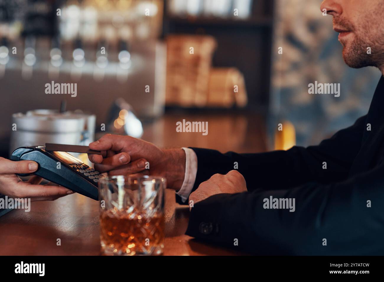Close-up of handsome young businessman making a contactless payment ...