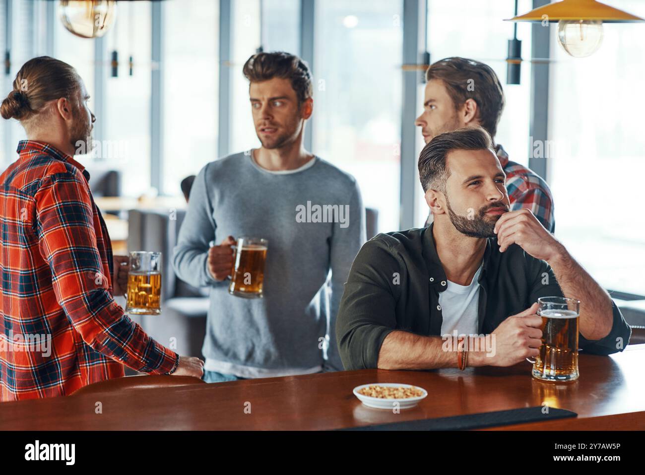 Group of young men in casual clothing enjoying beer and communicating ...