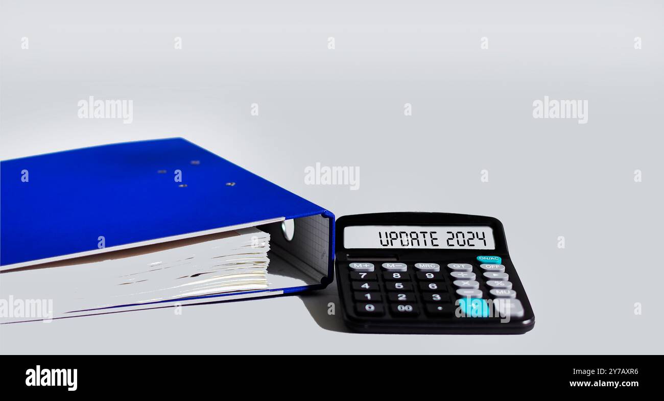 Calculator with UPDATE 2024 on the display, next to a blue folder on a ...