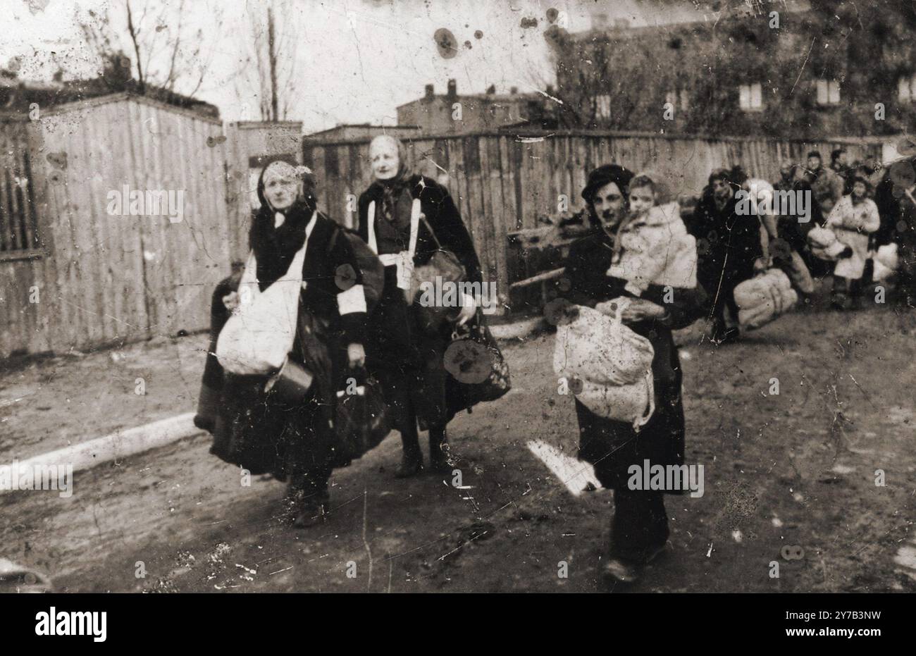 Elderly women carrying young children and bundles of personal ...