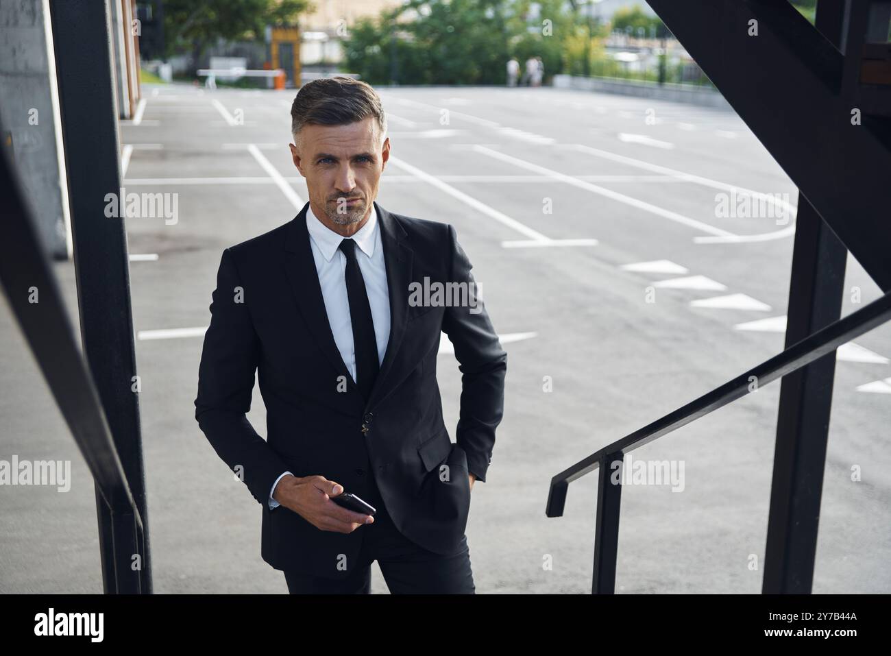 Confident mature businessman carrying mobile phone while walking ...