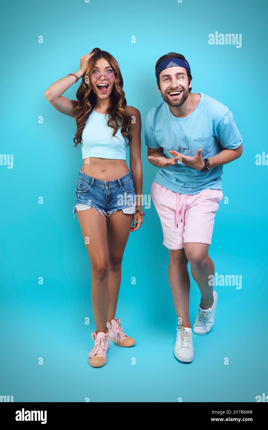 Full length of surprised young couple having fun while standing against ...