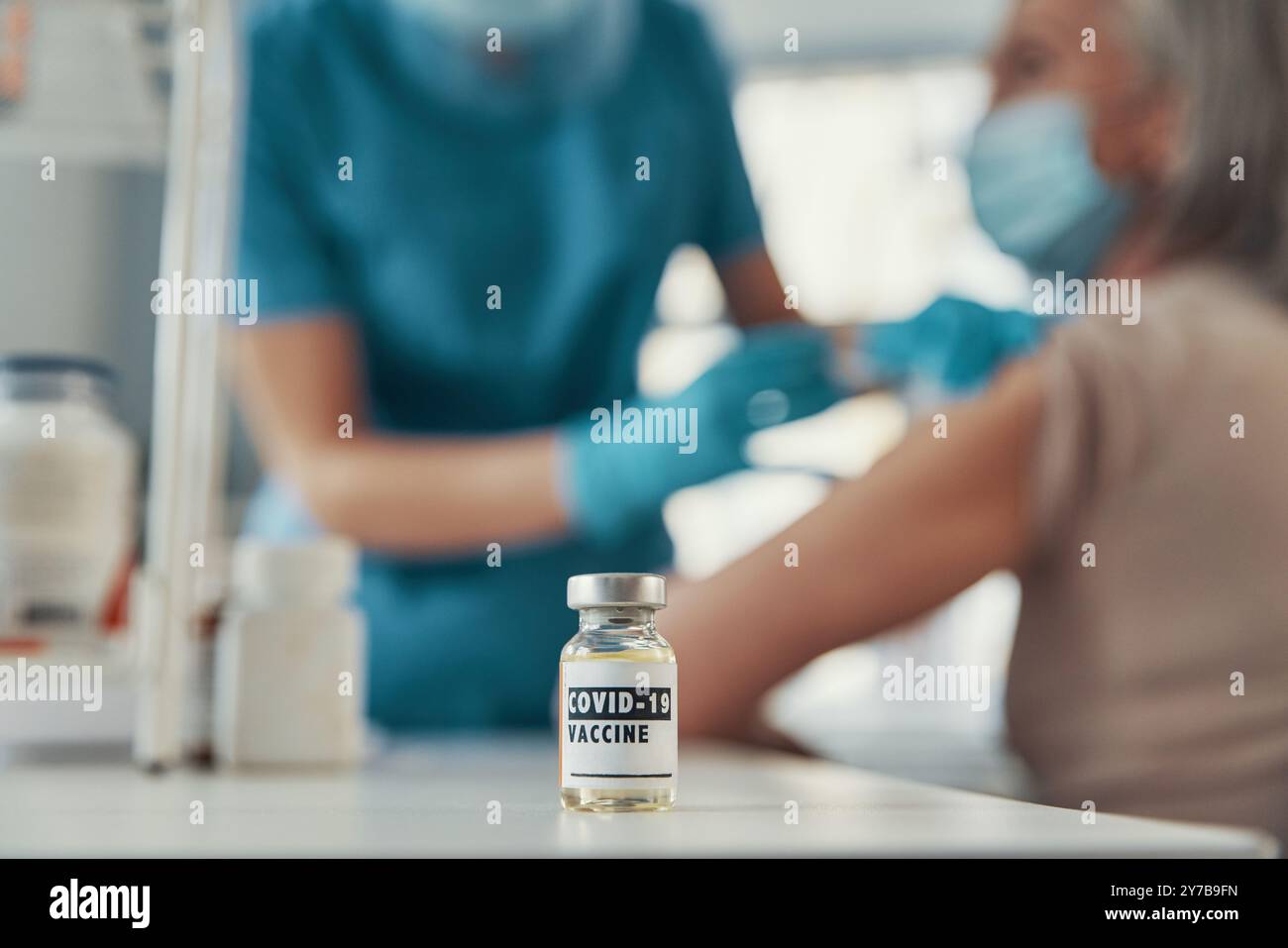 Female nurse making coronavirus vaccination to mature woman while ...