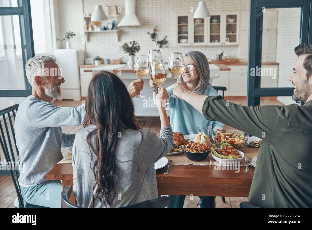 Happy multi-generation family toasting each other and smiling while ...