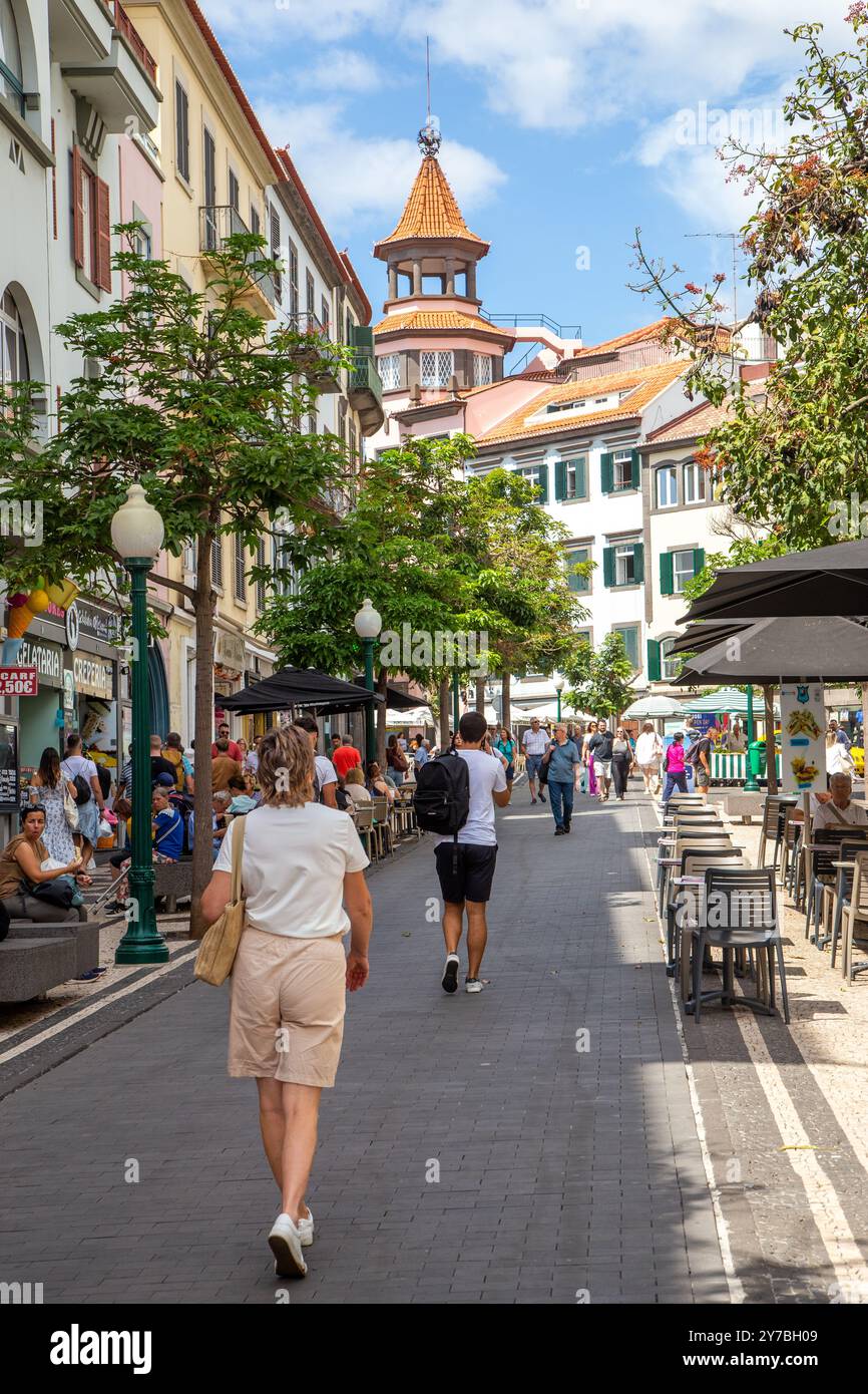 People talking walking along a street between tables of tourists and ...