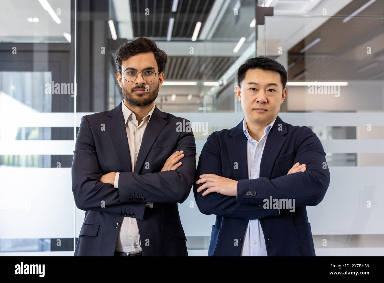Two business professionals stand confidently with arms crossed in ...