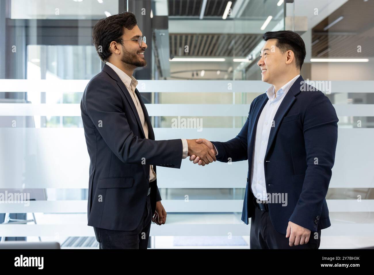 Two businessmen exchange a confident handshake in modern office ...