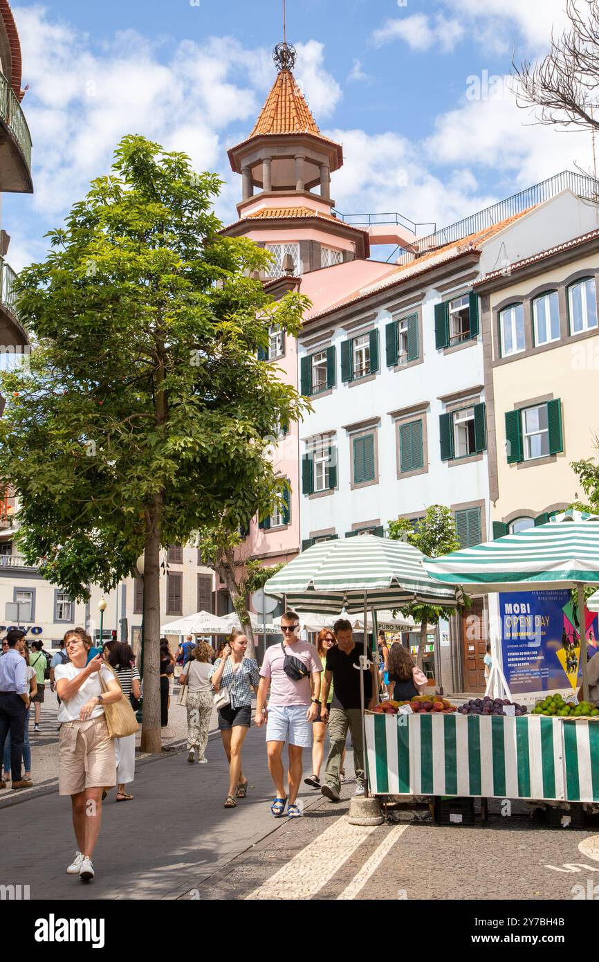 People talking walking along a street between tables of tourists and ...