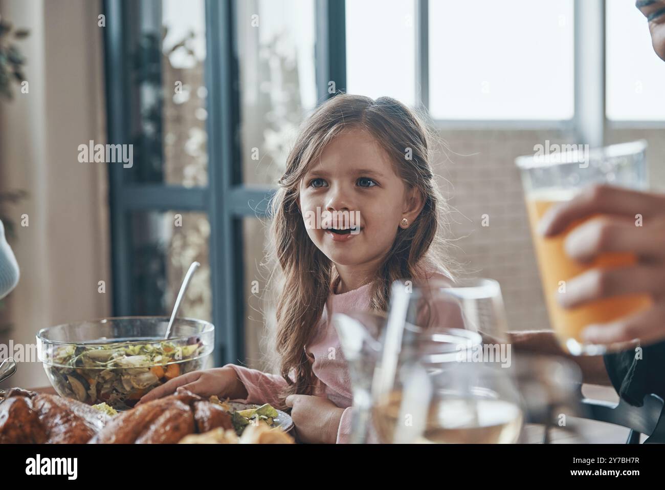 Happy little girl smiling while having dinner with family Stock Photo ...