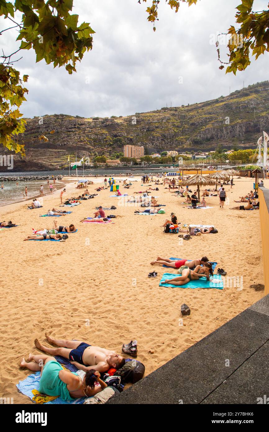 Holidaymakers sunbathing on the artificial beach of imported sand from ...