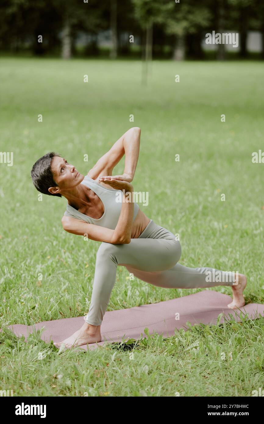 Senior fit woman standing in triangle pose, she enjoying process and ...