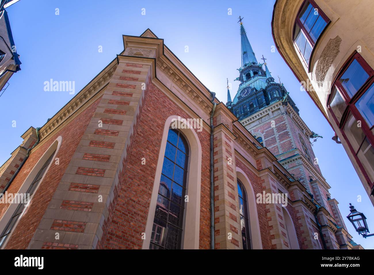 Imposing red brick facade with Gothic spire against blue sky ...