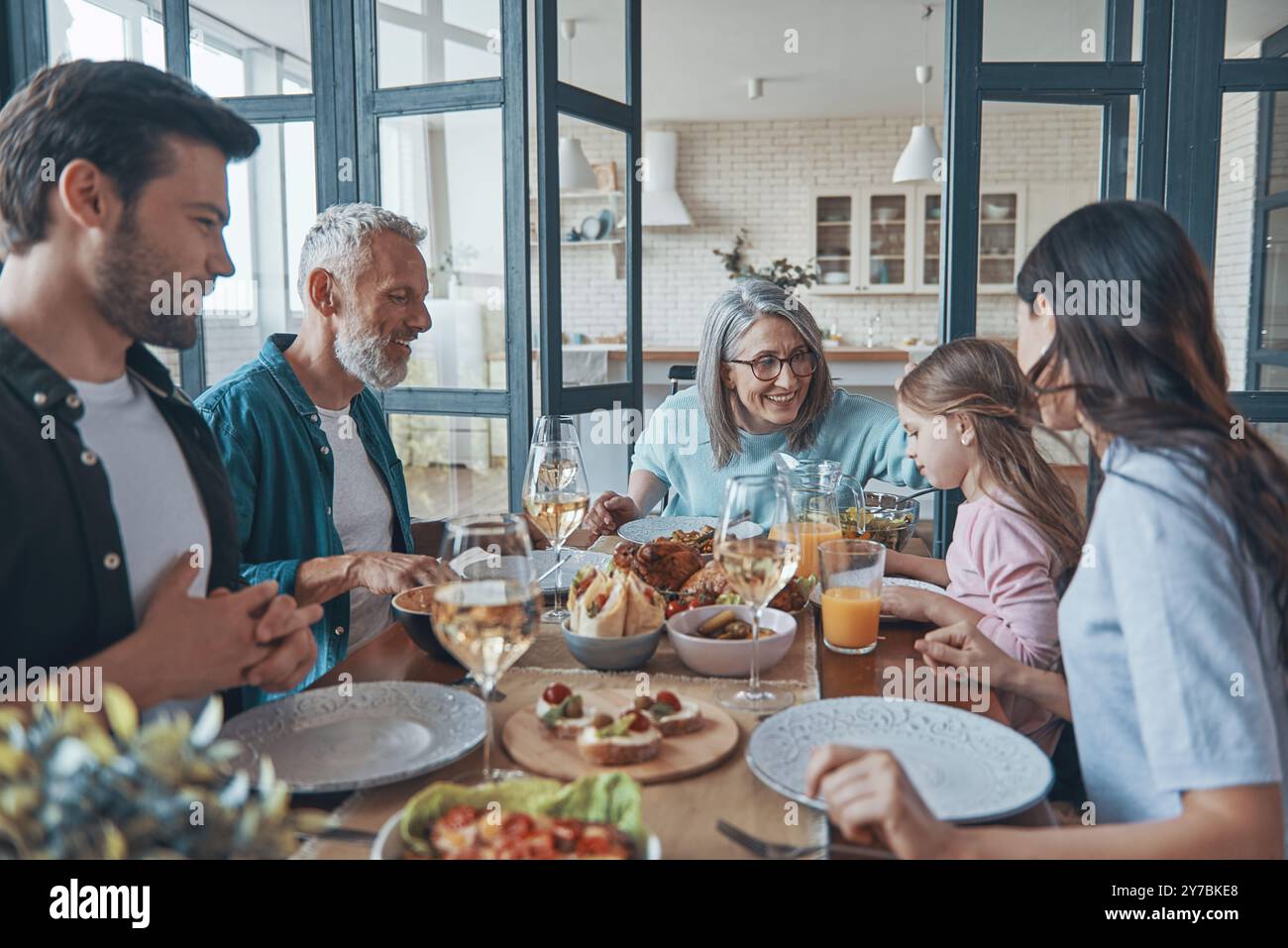 Happy multi-generation family smiling while having dinner together ...