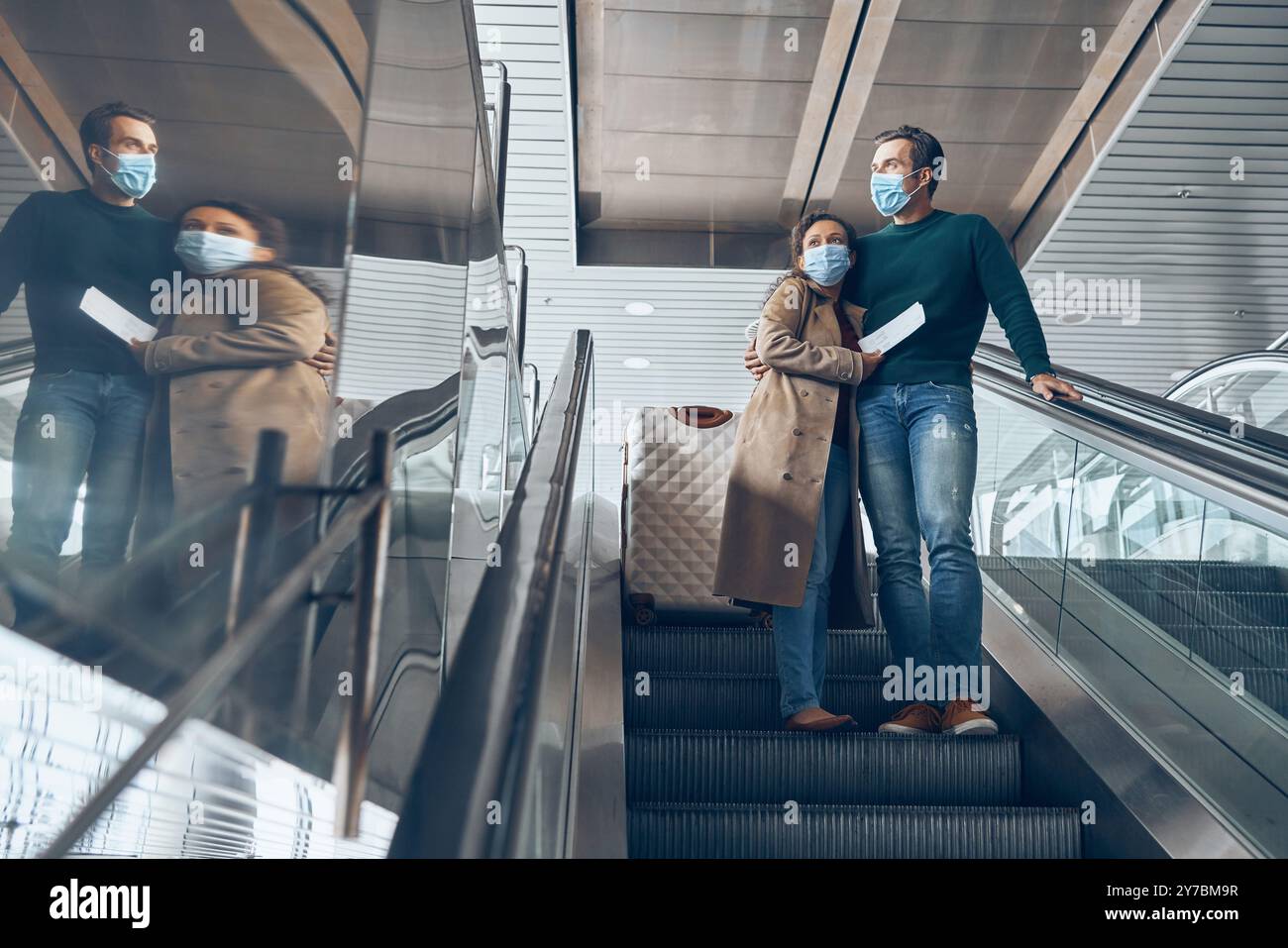 Mature couple carrying tickets while moving by escalator in airport ...
