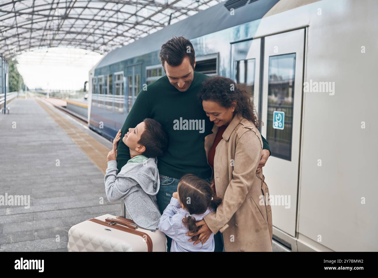 Happy family with two little kids bonding while standing on railroad ...