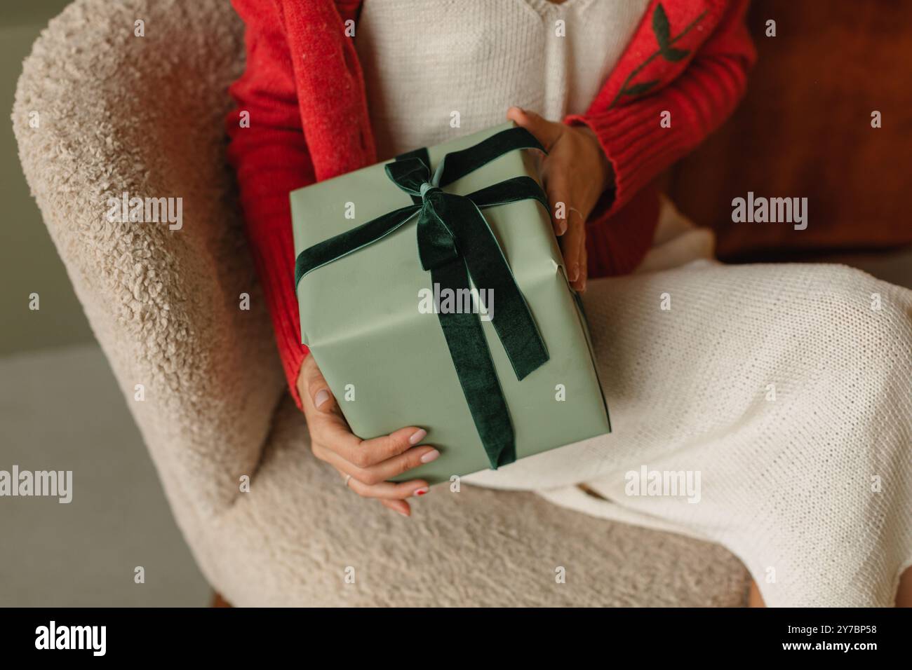Close-up of a woman siting on a chair holding a wrapped gift Stock ...