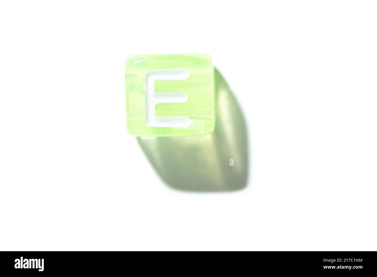 Translucent green cube with letter e casting shadow on white background ...