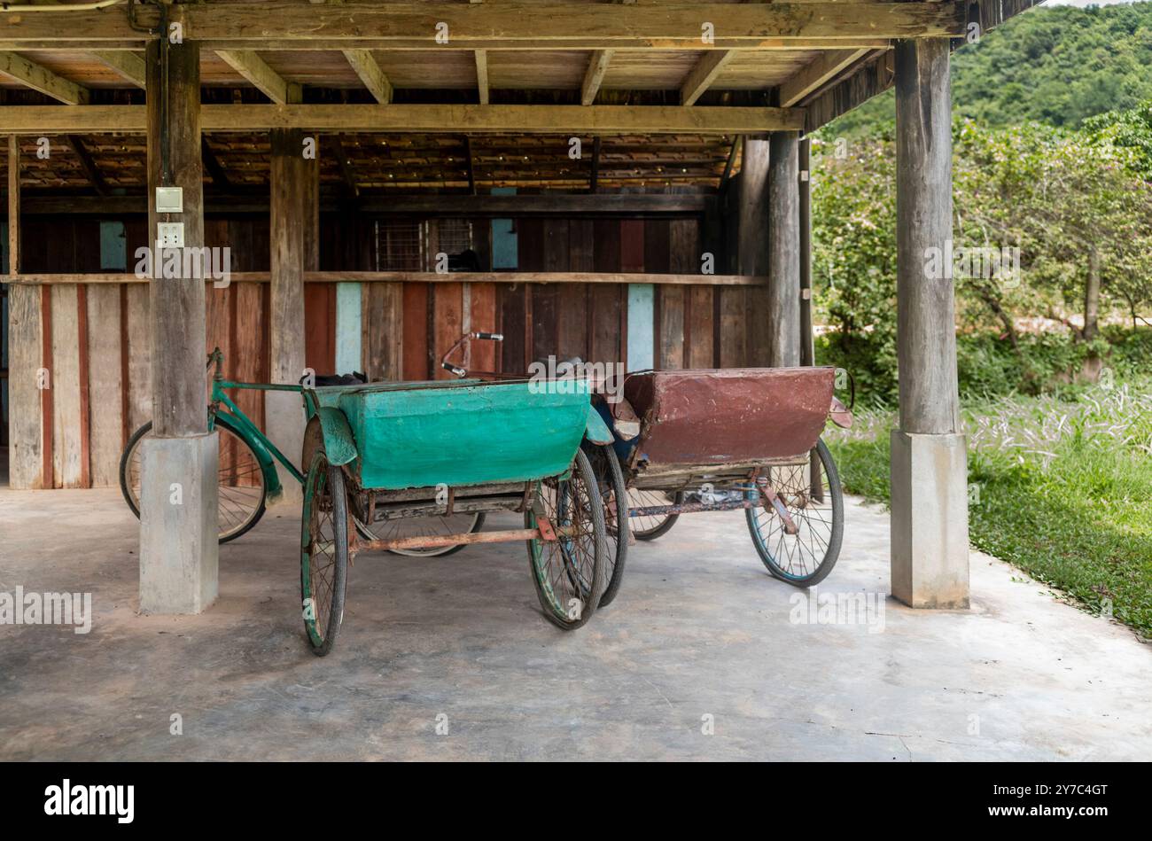 Old cycle rickshaws parked under a house in Kampot in Cambodia Stock ...