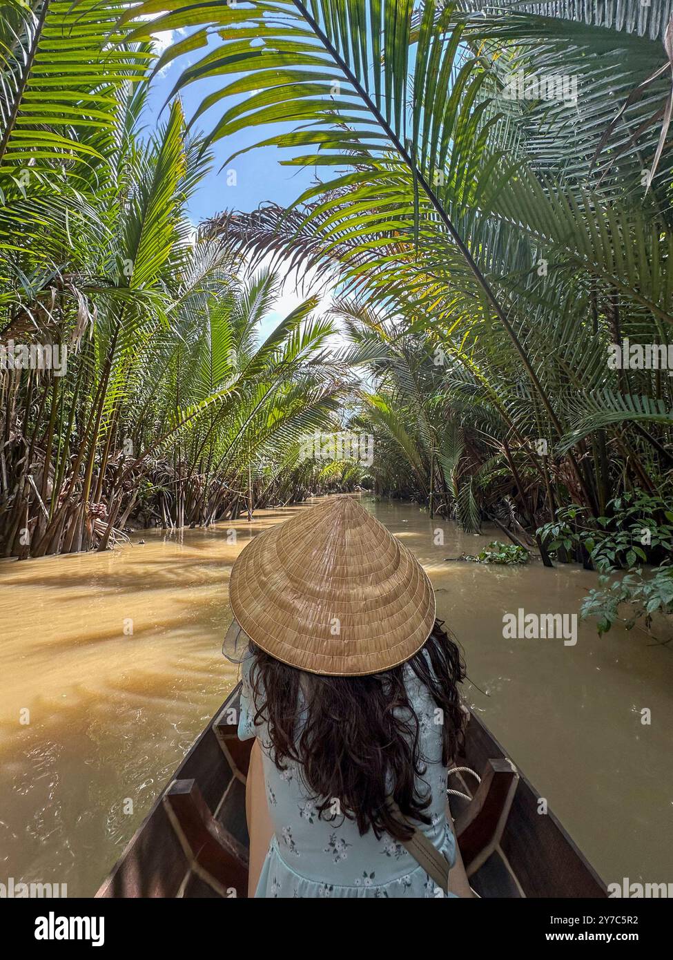 A young woman on a sampan in the narrow water canals in Ben Tre in ...