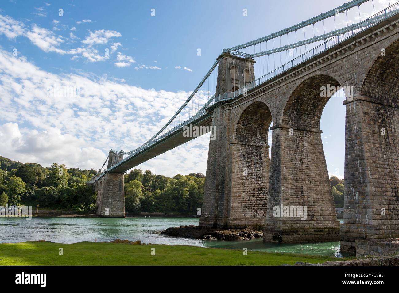 Menai suspension bridge. A stone arch bridge spans a river under a ...
