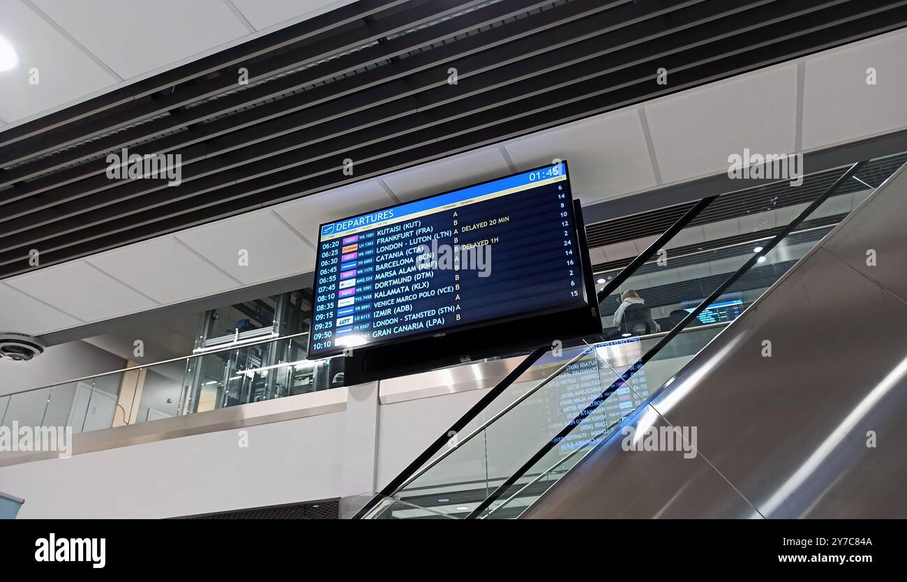 A digital departure board in an airport displays flight schedules ...