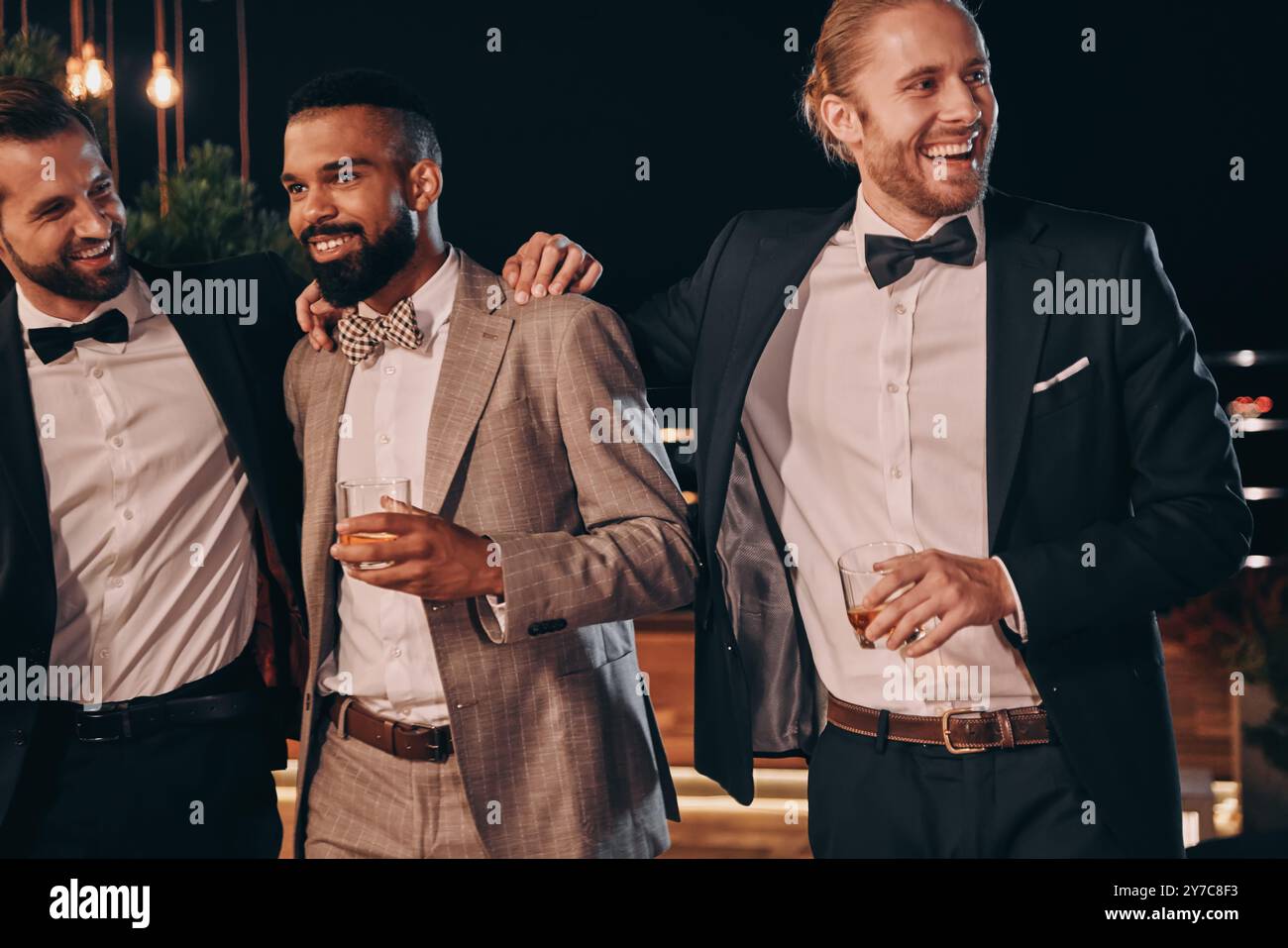 Three handsome men in suits bonding and drinking whiskey while spending ...