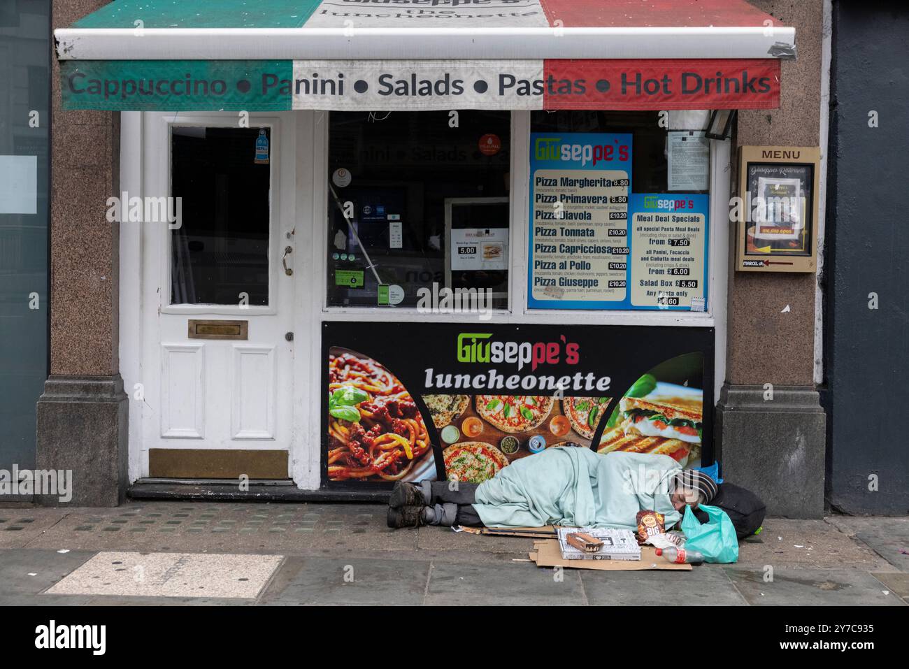 Homeless man sleeps underneath a blanket whilst rough sleeping in the ...