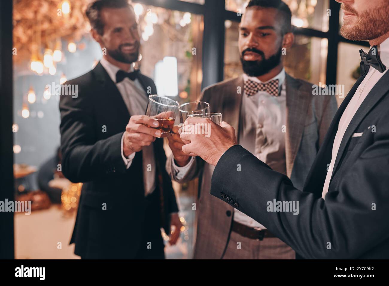 Three handsome men in suits toasting with whiskey and smiling while ...