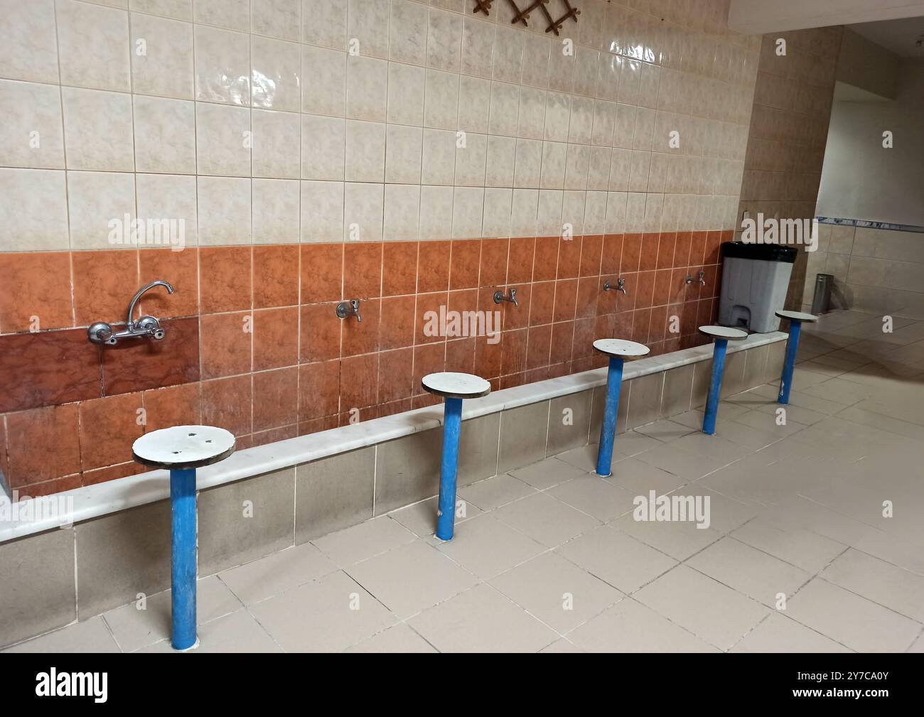 A wudu area in a mosque, featuring a row of faucets for washing hands ...