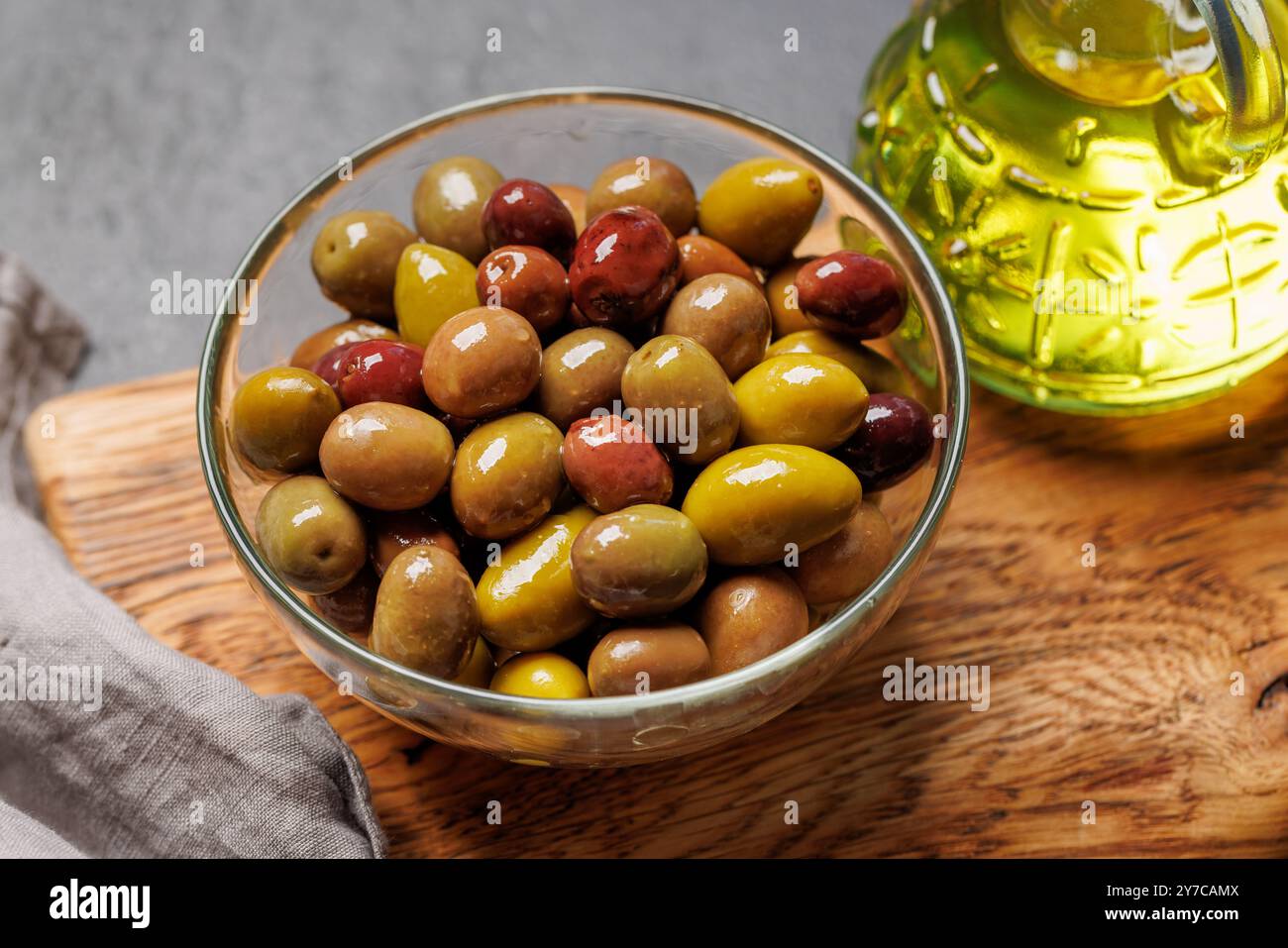 An assortment of various olives presented in a bowl and olive oil ...