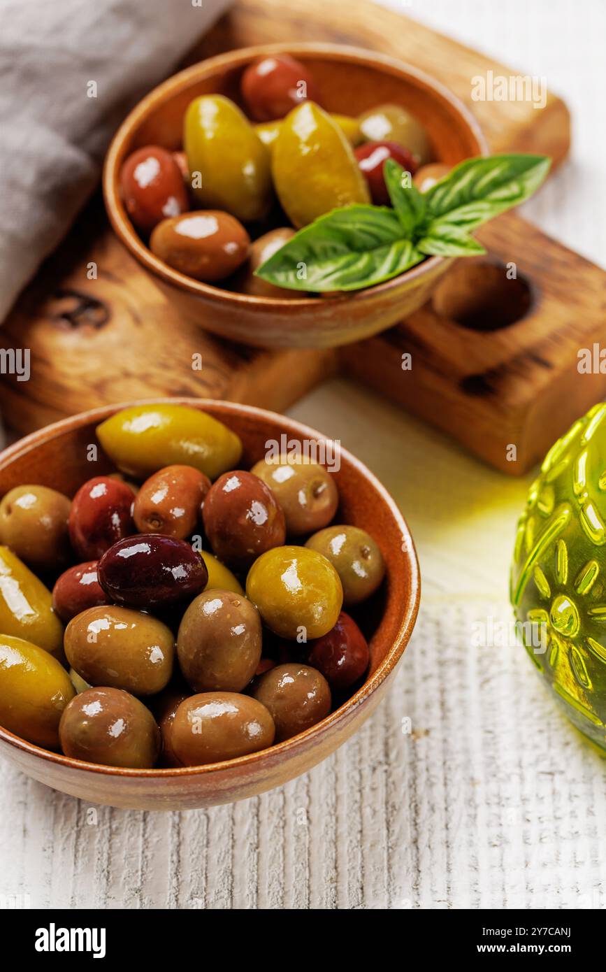 An assortment of various olives presented in a bowl and olive oil ...