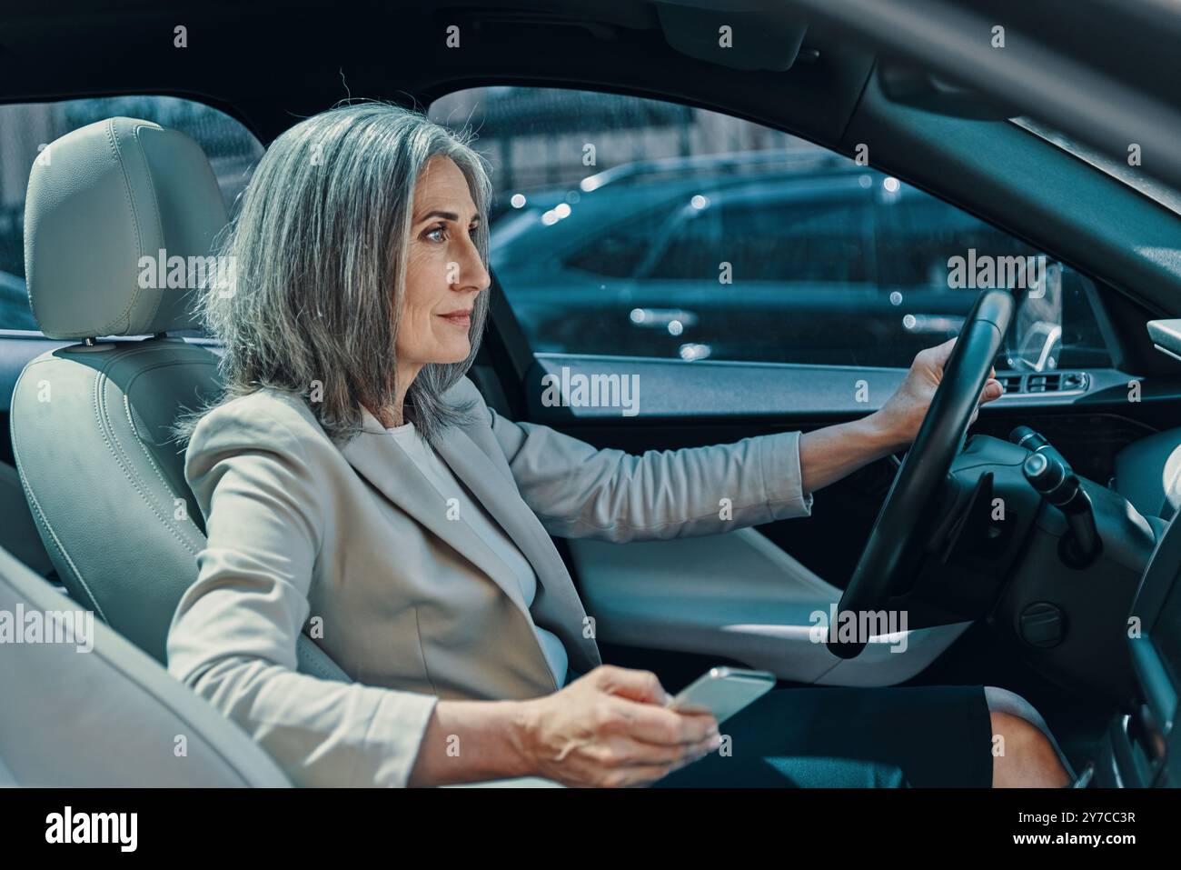 Mature beautiful woman in smart casual wear smiling and using phone ...