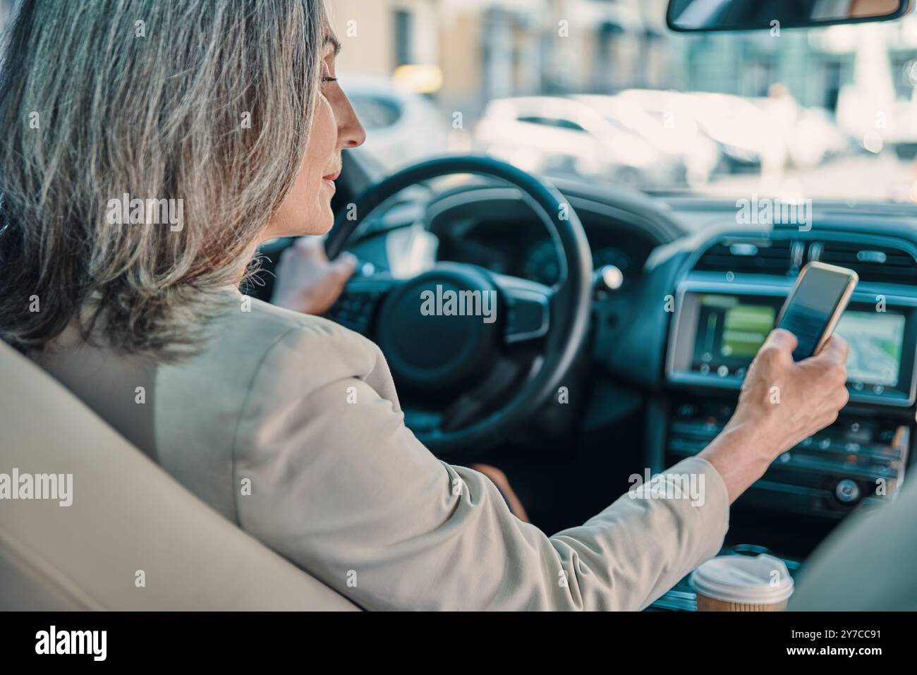 Rear view of mature beautiful woman in smart casual wear using phone ...