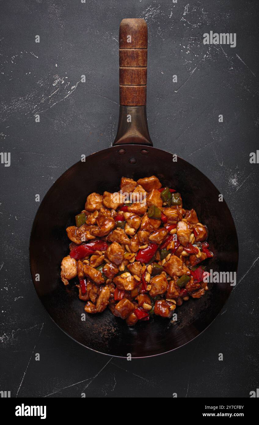 Traditional Chinese dish kung pao chicken in wok pan on dark background ...