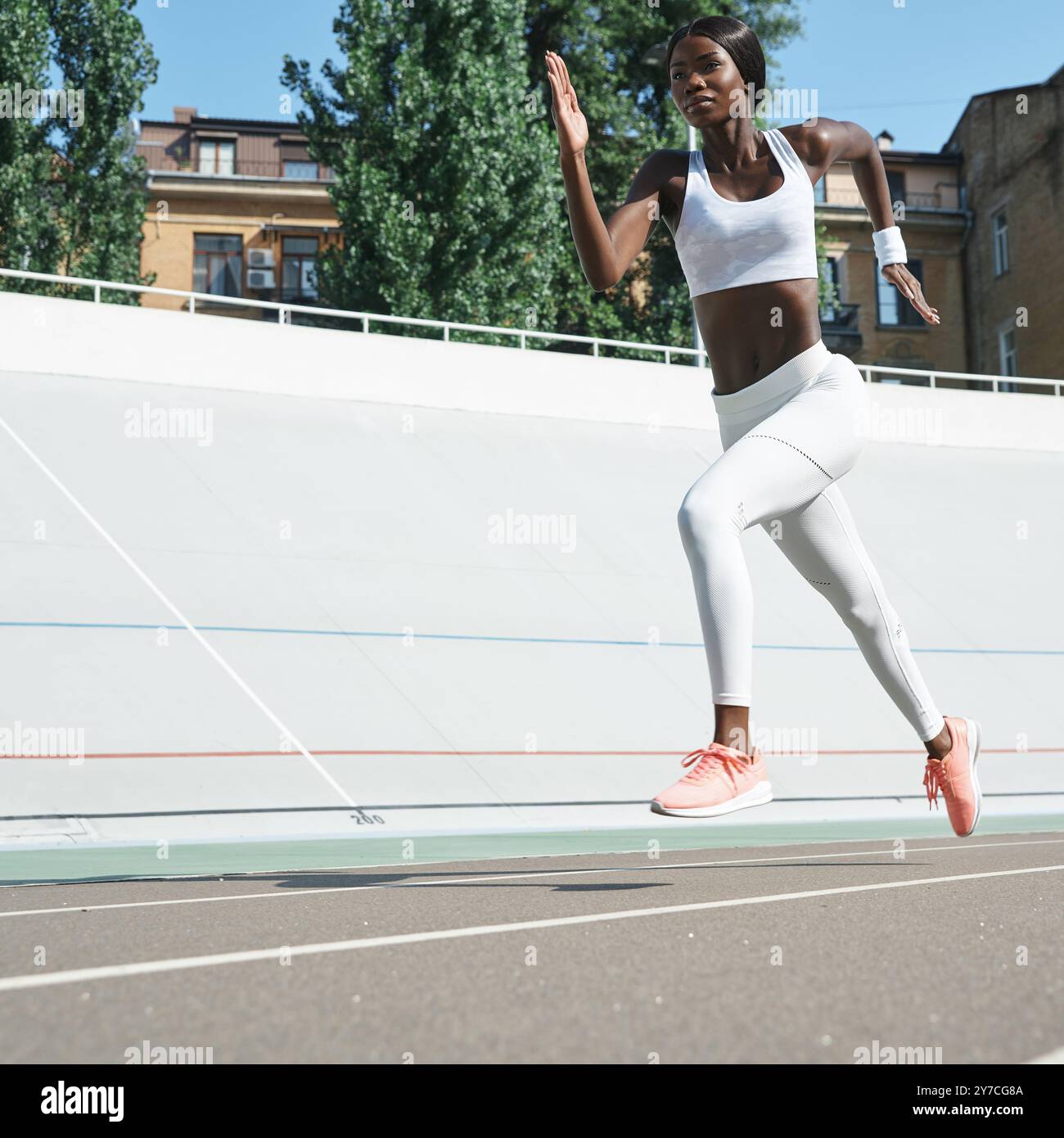 Beautiful young African woman in sports clothing running on track ...