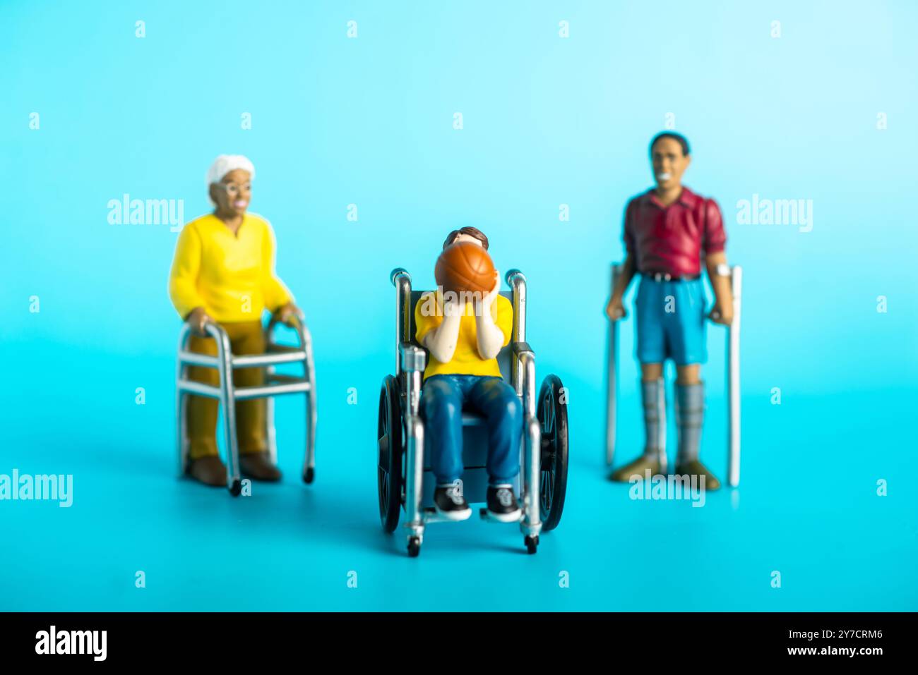 Miniature figures representing disability and support on blue ...