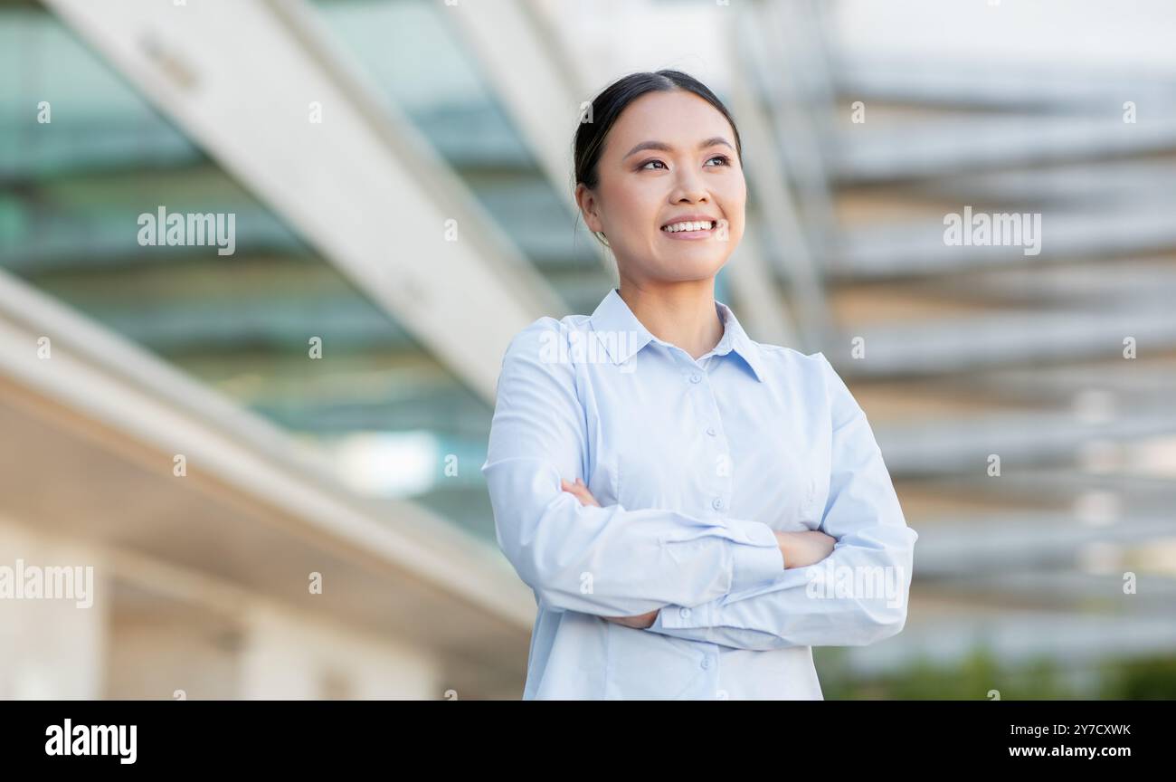 Confident professional woman smiling outdoors in a modern urban setting ...