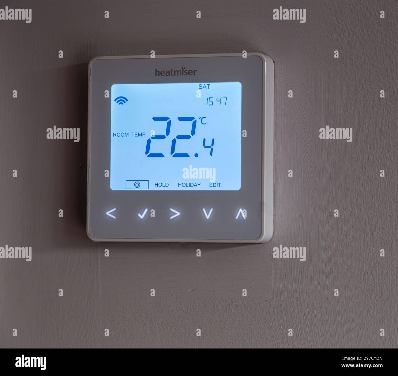 Digital thermostat mounted on a wall showing a room temperature of 22.4 ...