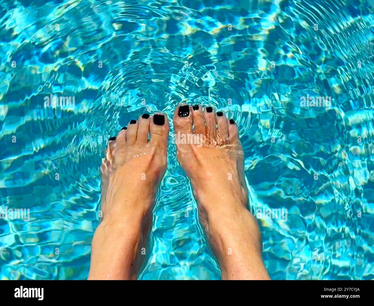 Overhead view of a woman sitting at the edge of a swimming pool ...