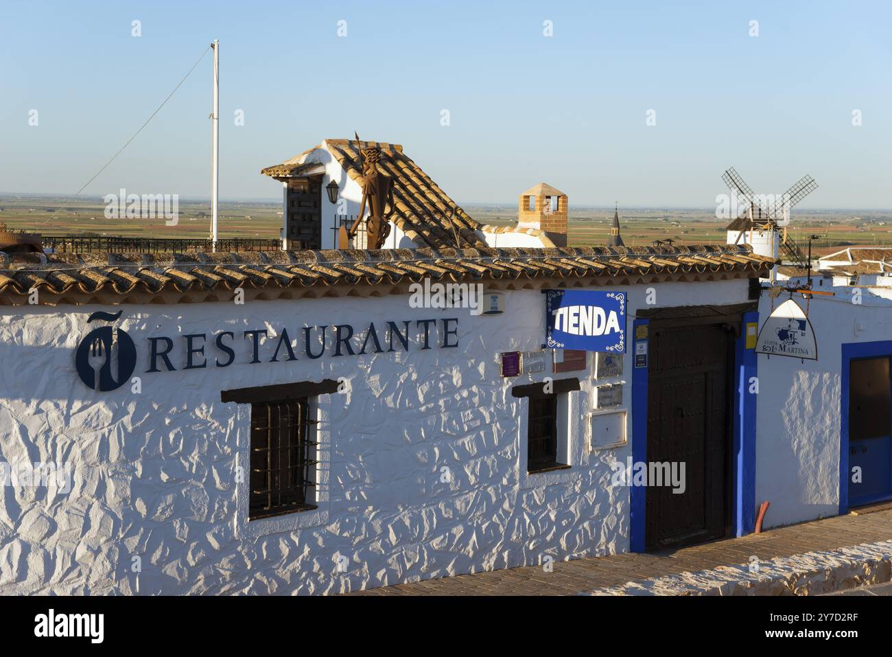 Rustic building with restaurant sign and white-blue walls, windmills in ...