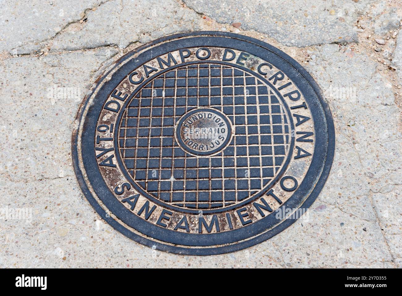 A round metal manhole cover with text engraving on a tarmac road ...