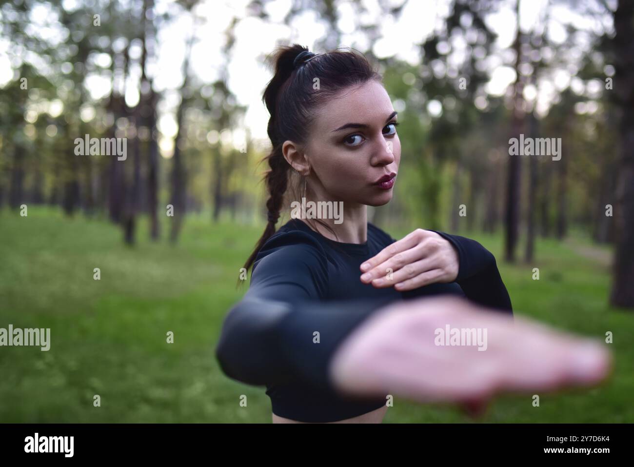 Young woman doing martial arts training in sporty black top holding ...