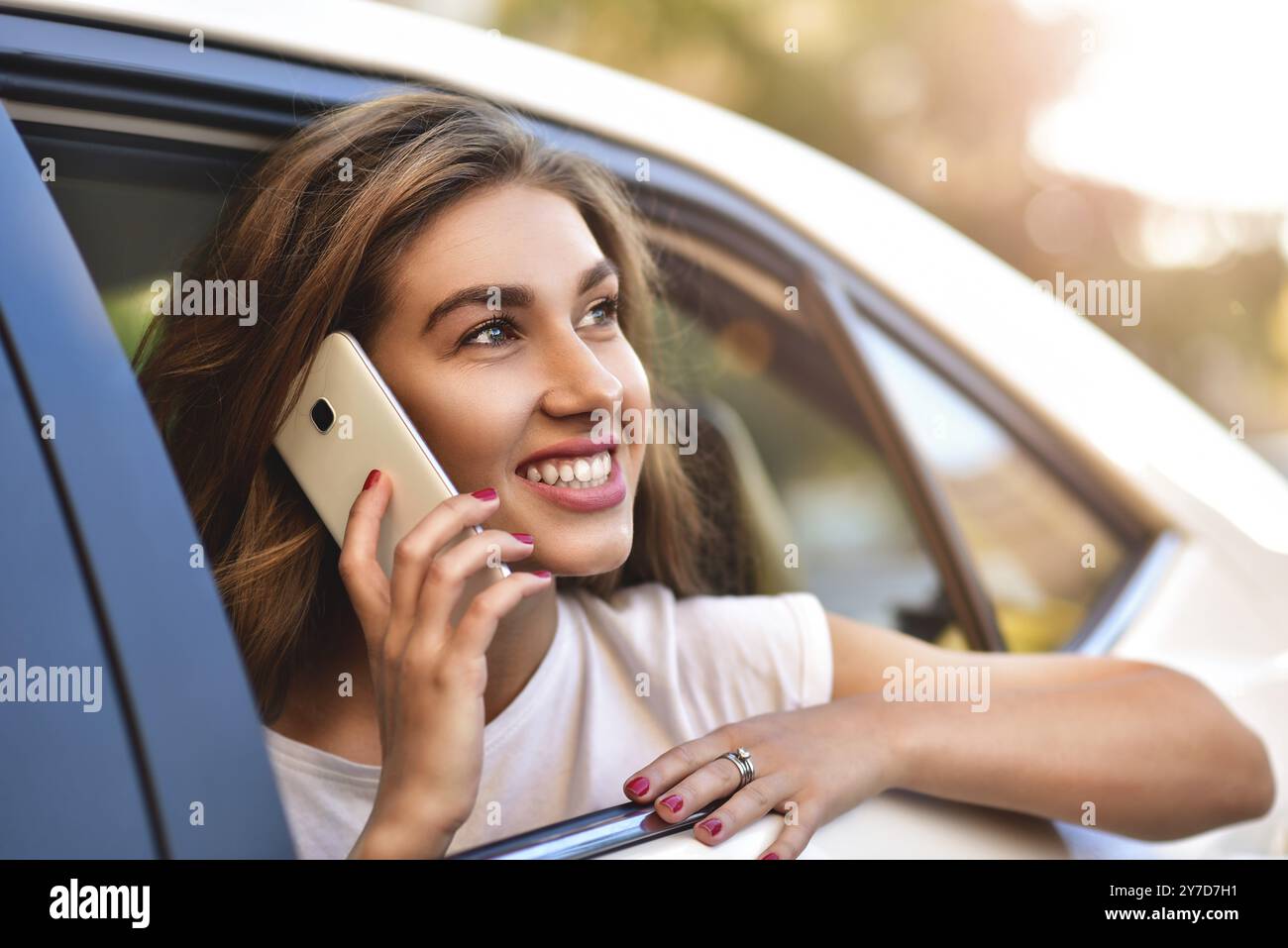 Beautiful woman with phone smiling while sitting on the back seat in ...