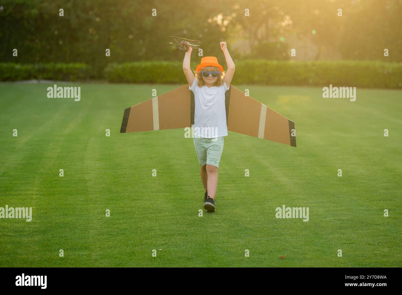 Kid pilot aviator with with paper wings dreams of traveling in summer ...