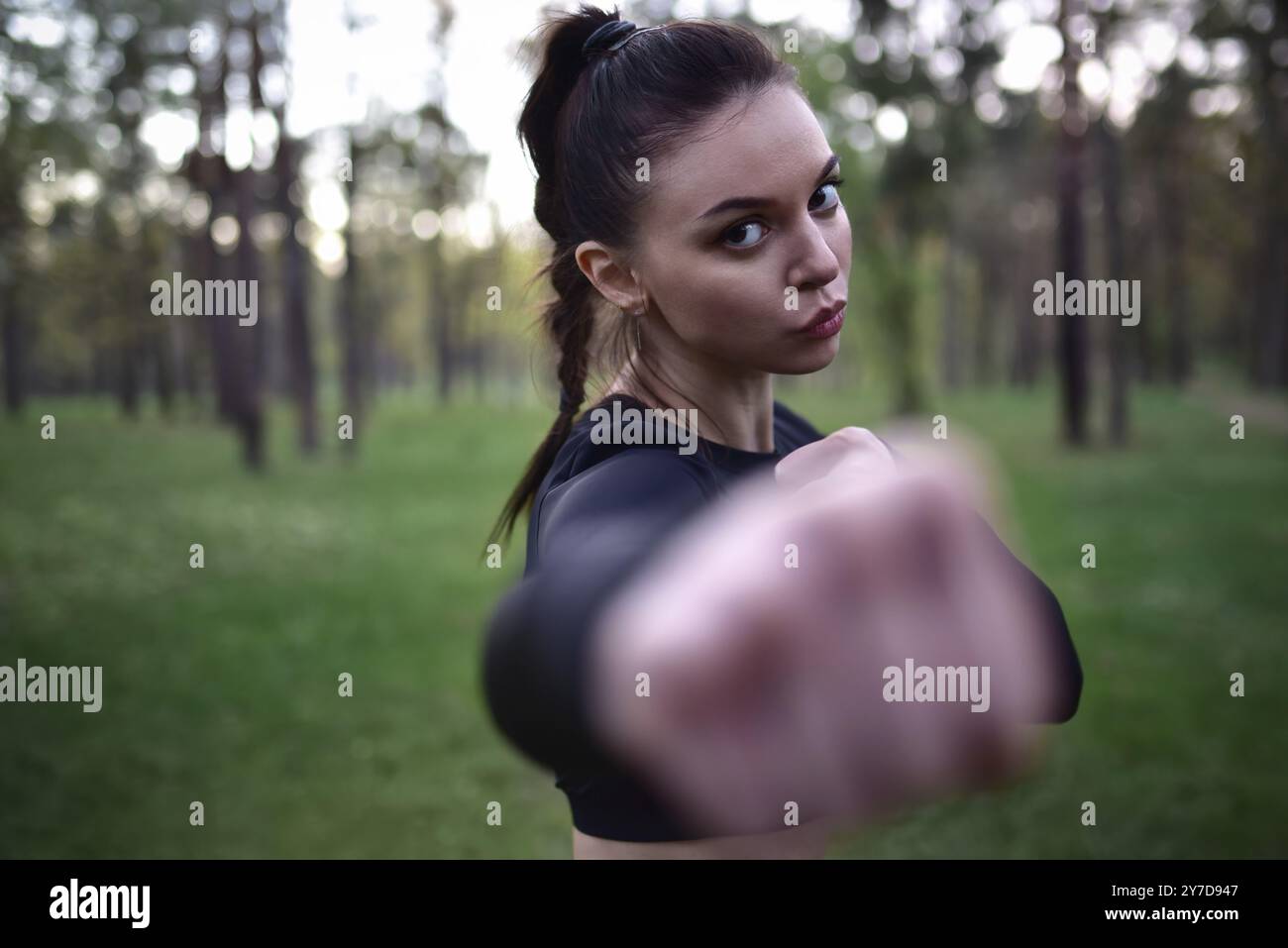 Young woman doing martial arts training in sporty black top holding ...