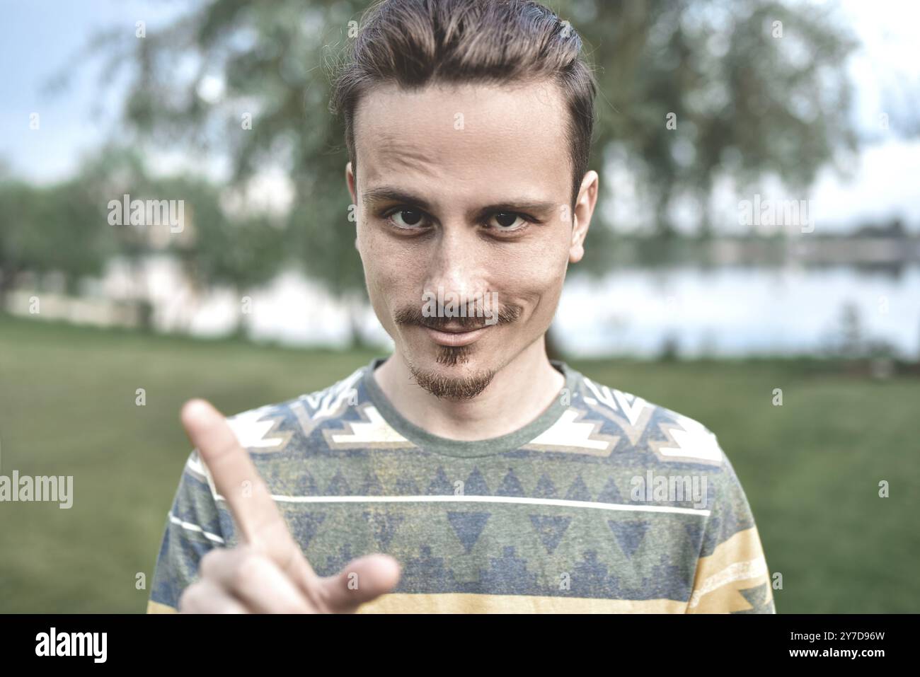 A guy with a sly expression on his face, shows a finger gesture, do not ...